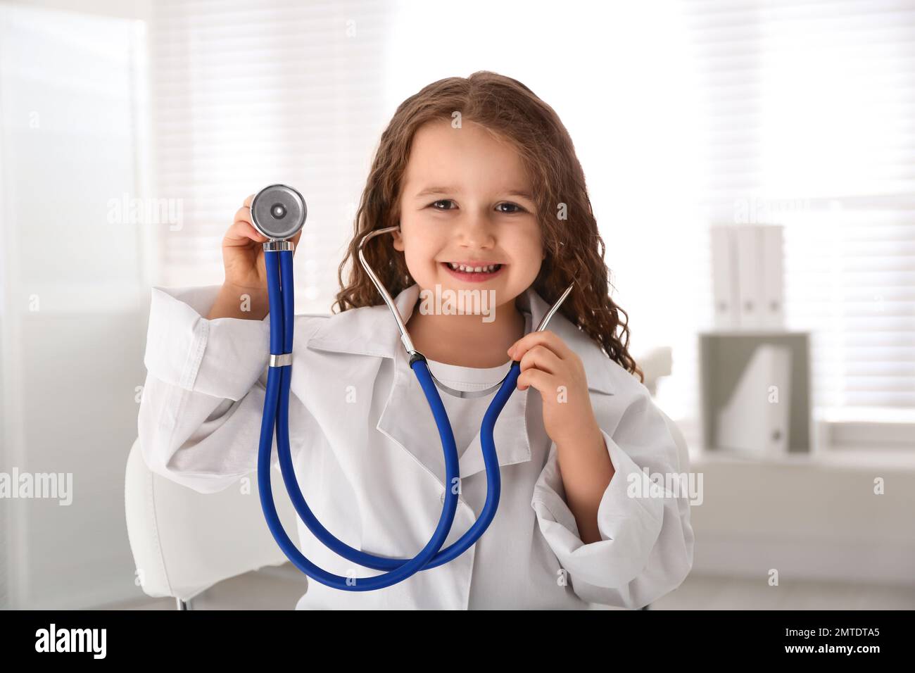 Cute little girl playing doctor in clinic Stock Photo - Alamy
