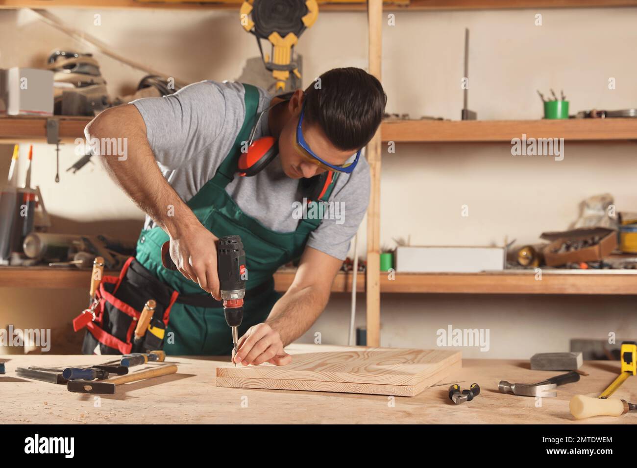 Professional carpenter twisting screw with drill at workbench Stock ...