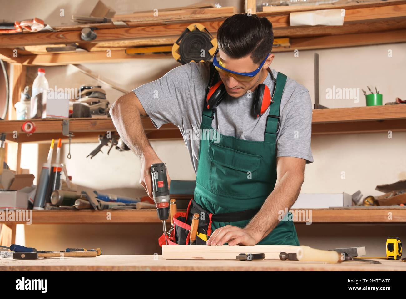 Professional carpenter twisting screw with drill at workbench Stock ...