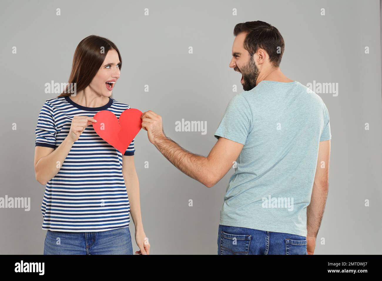 Couple tearing paper heart on light grey background. Relationship ...