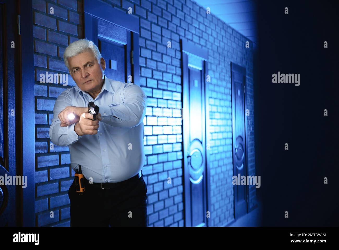 Professional security guard with gun and flashlight checking dark ...
