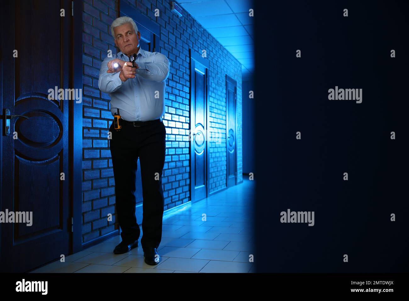 Professional security guard with gun and flashlight checking dark ...