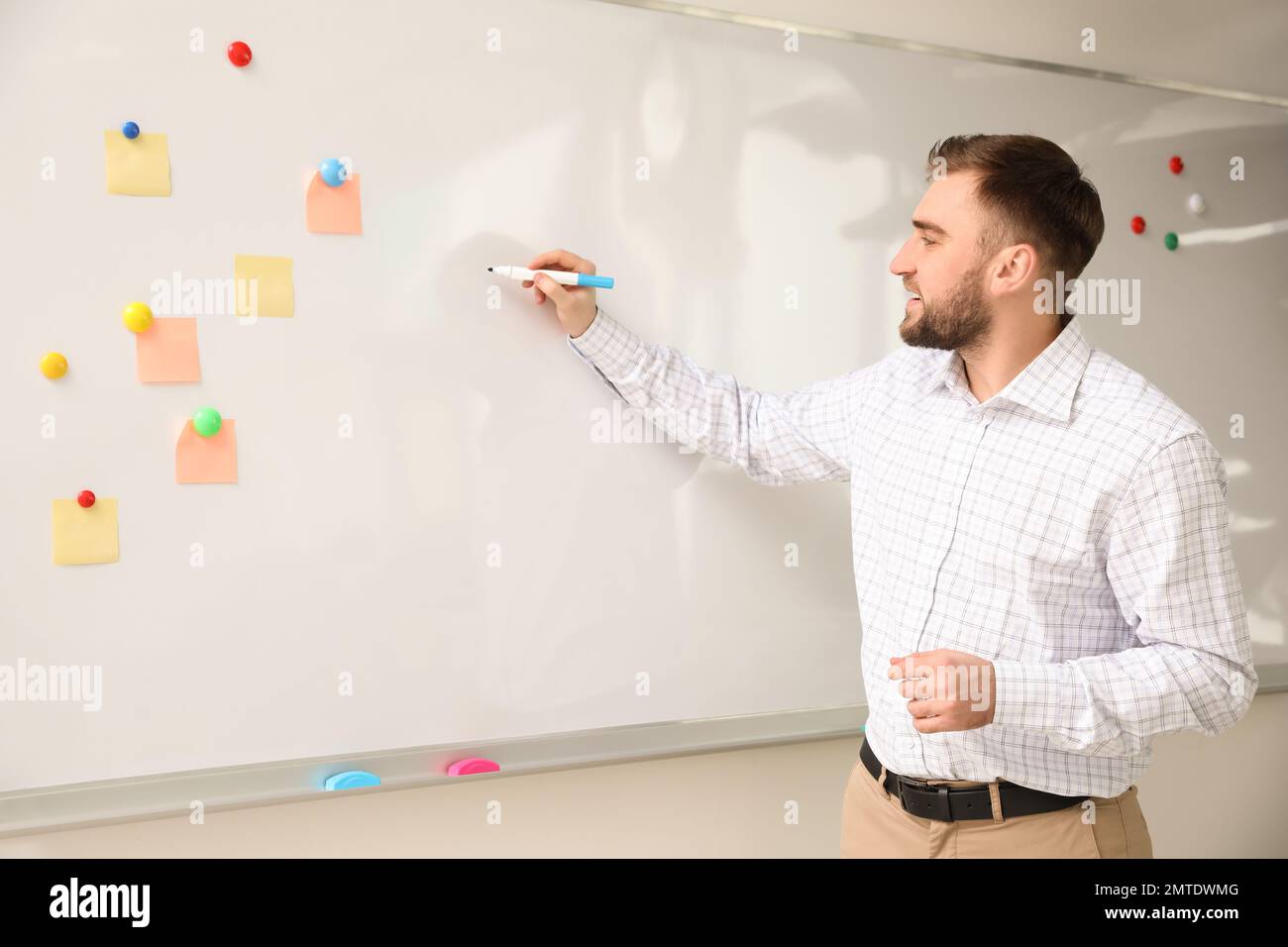 Portrait of young teacher writing on whiteboard in classroom Stock ...