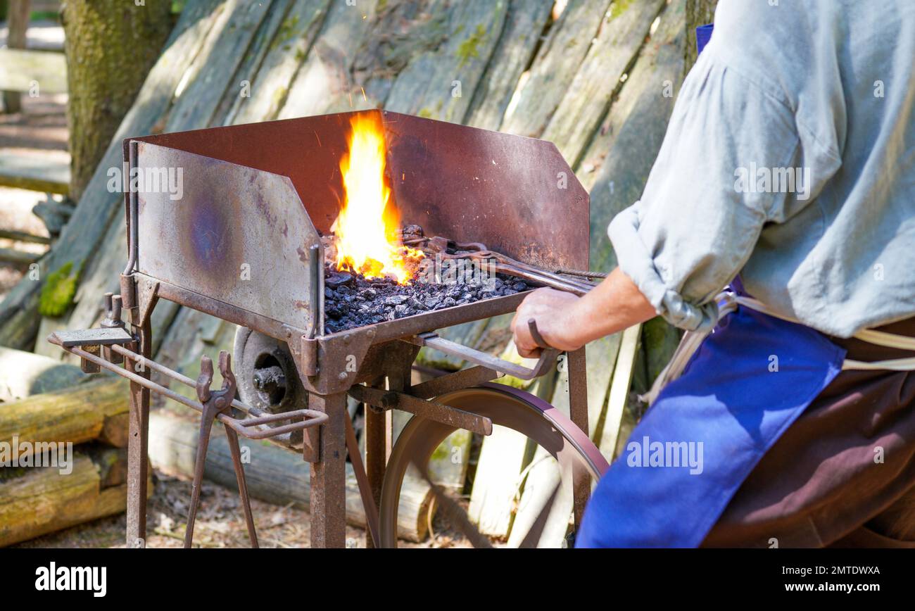 Blacksmith with red-hot iron at work Stock Photo - Alamy