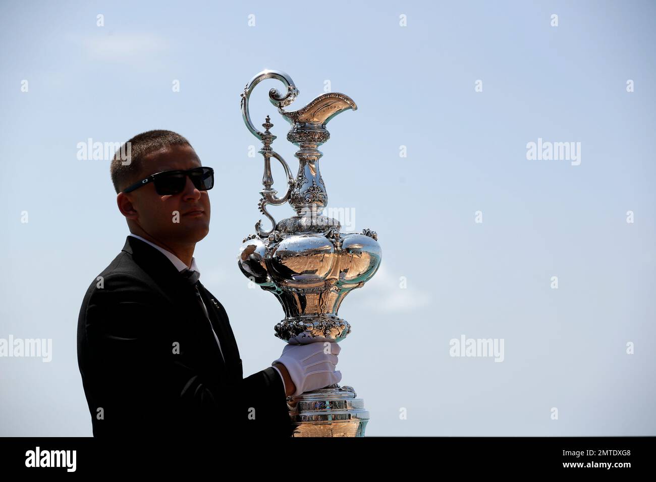 An attendant carries the America's Cup trophy, known as the "Auld Mug ...