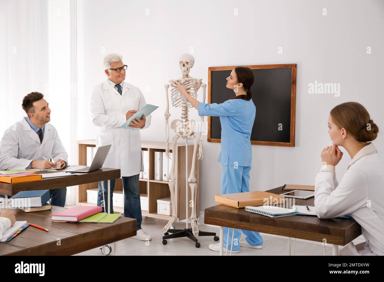 Medical students and professor studying human skeleton anatomy in ...