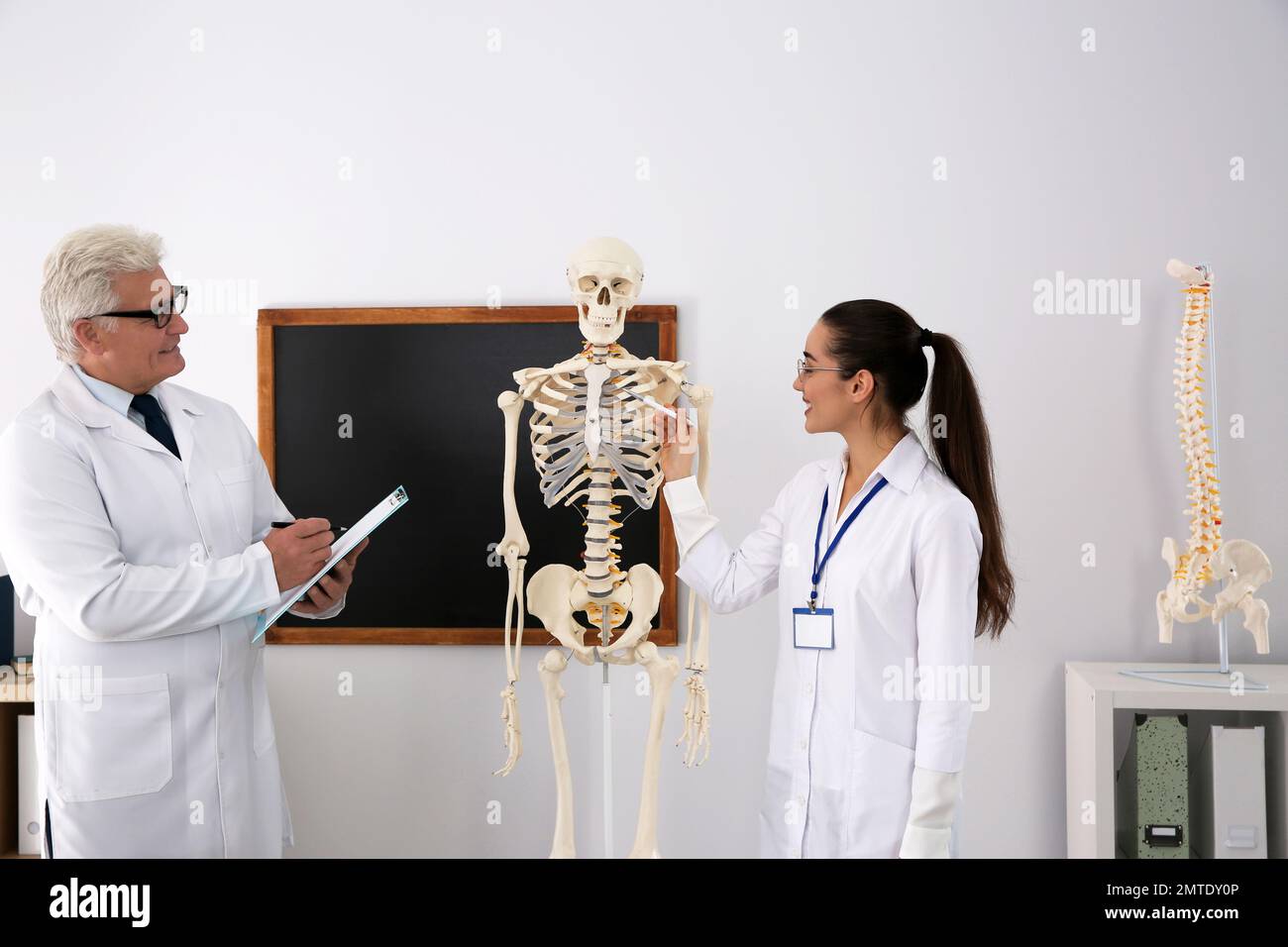 Medical student and professor studying human skeleton anatomy in ...