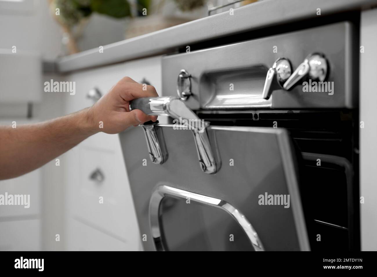 Man using modern oven in kitchen, closeup Stock Photo - Alamy