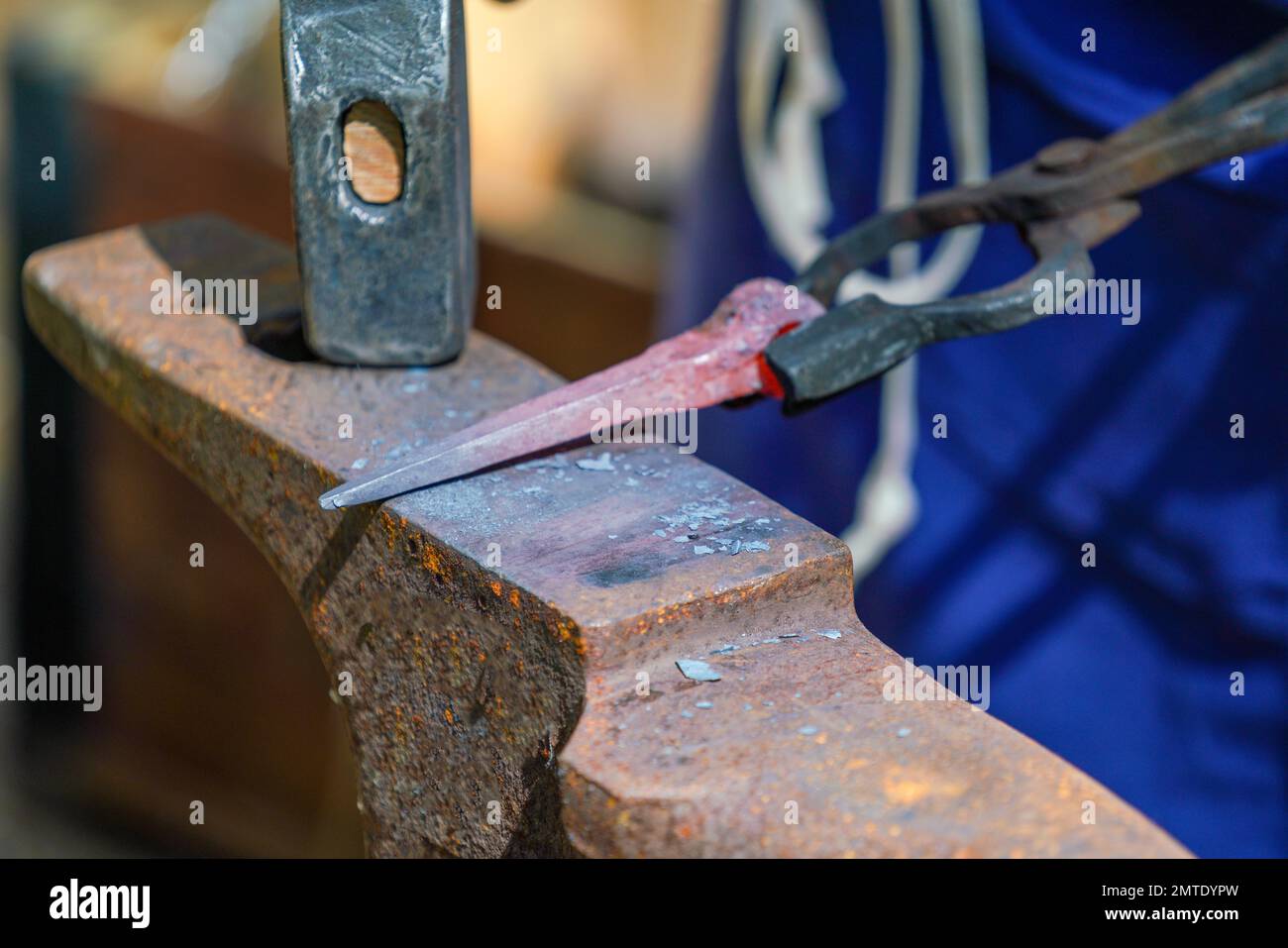 Blacksmith with red-hot iron at work Stock Photo - Alamy