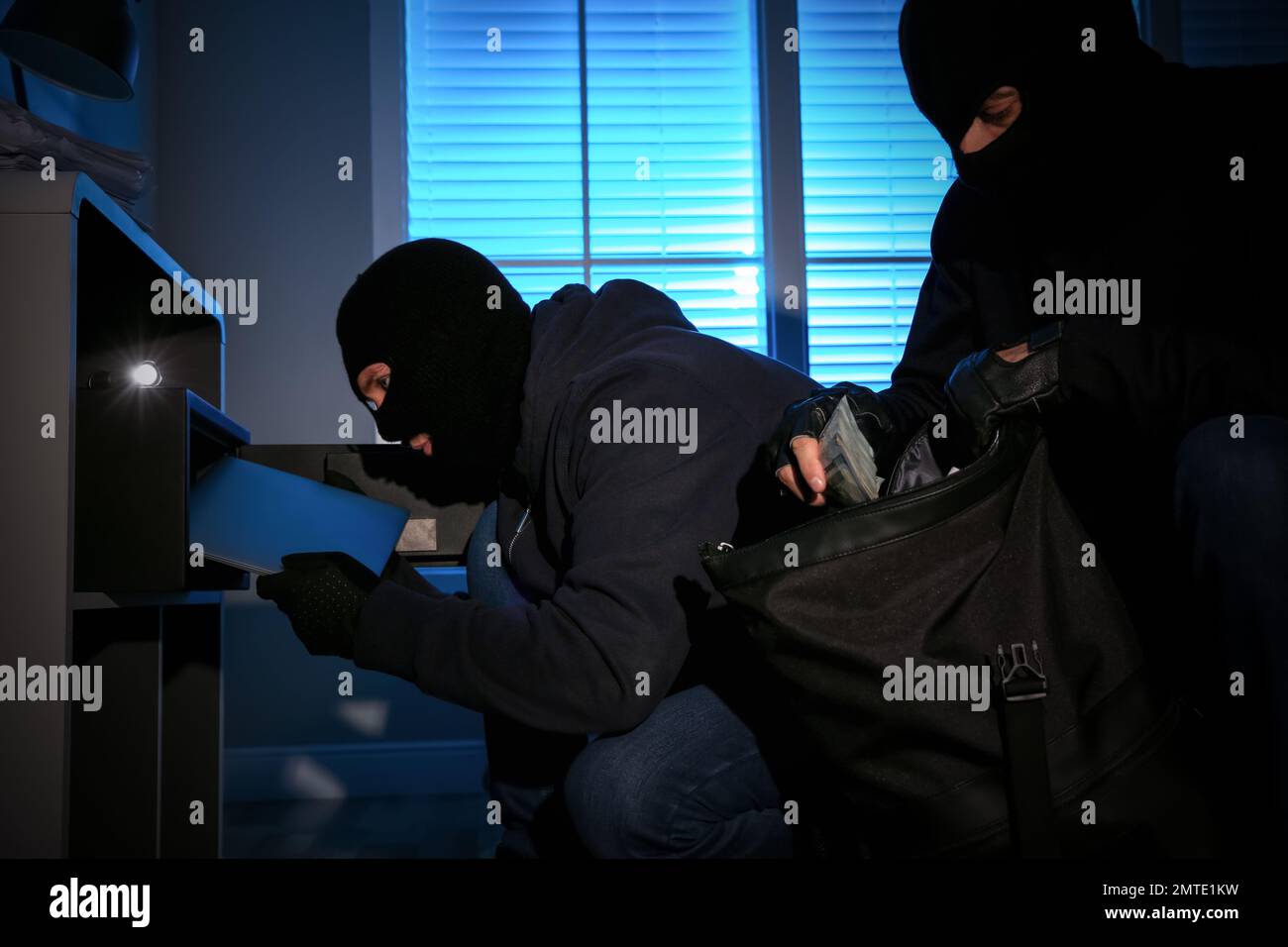 Thieves taking money and laptop out of steel safe indoors at night ...
