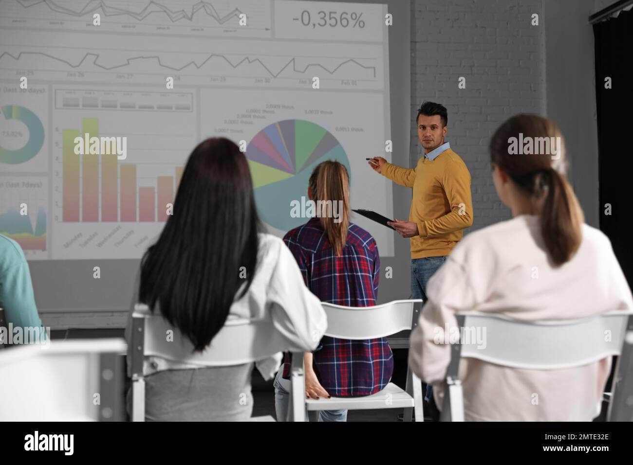 Male business trainer giving lecture in conference room with projection ...