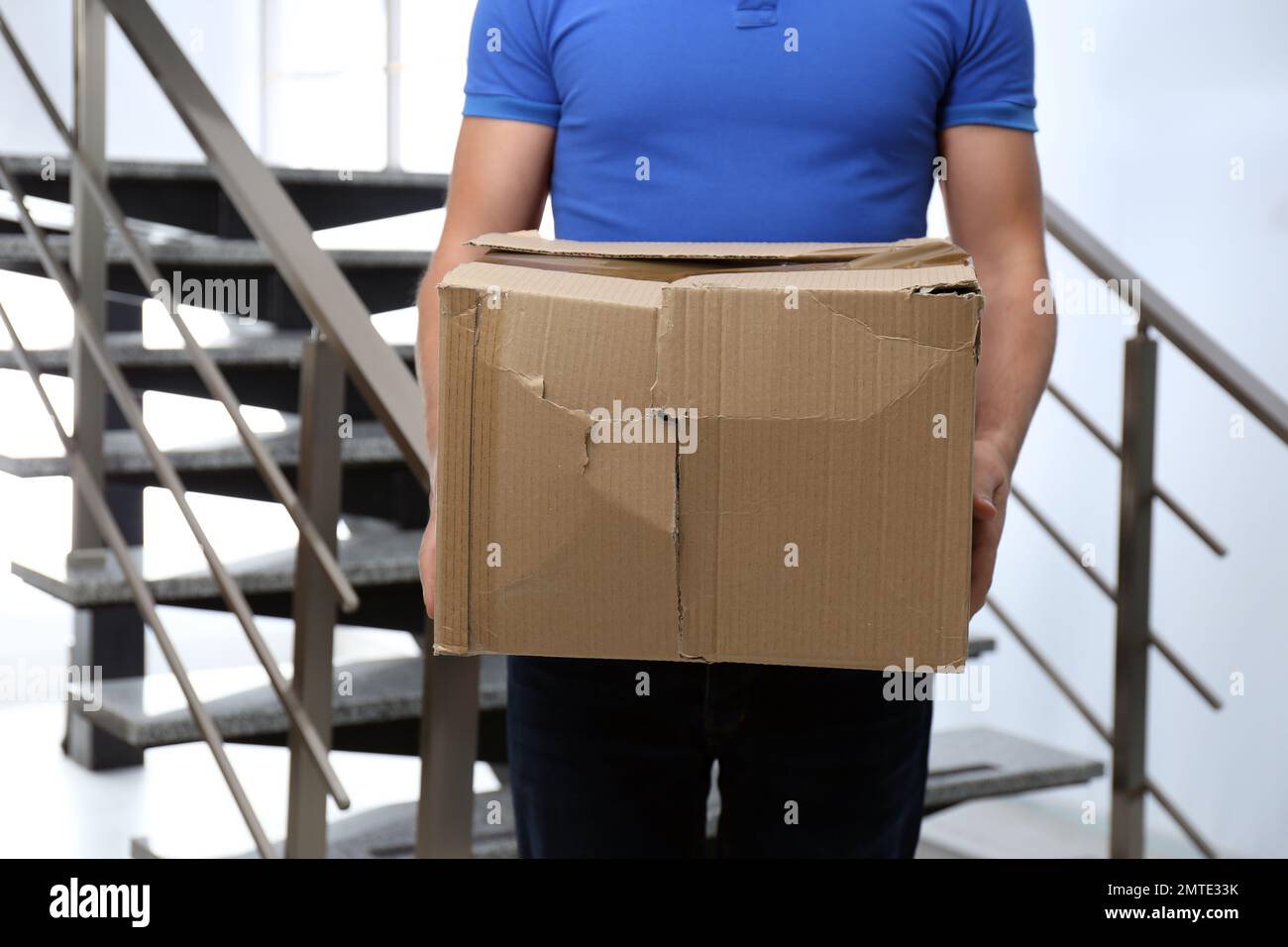 Courier with damaged cardboard box indoors, closeup. Poor quality ...