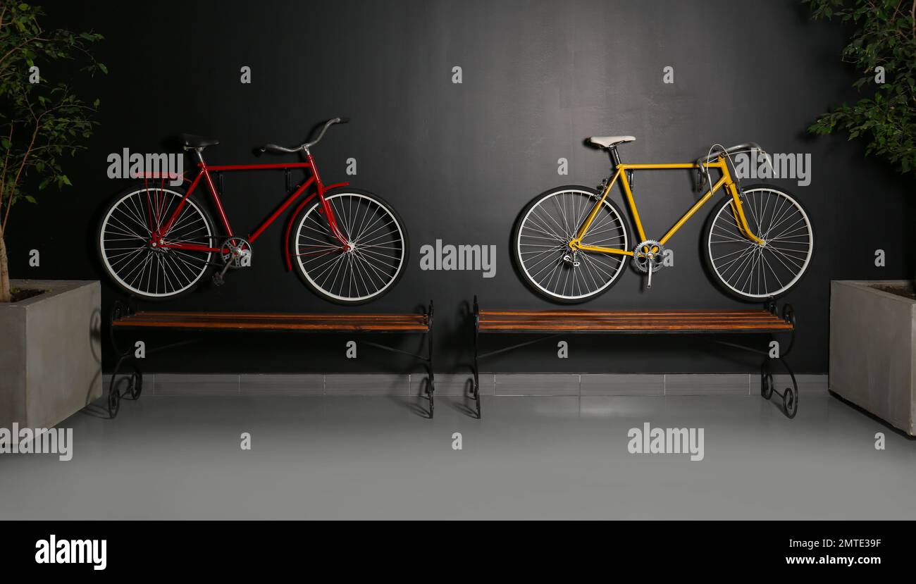 Color bicycles hanging on black wall indoors Stock Photo - Alamy