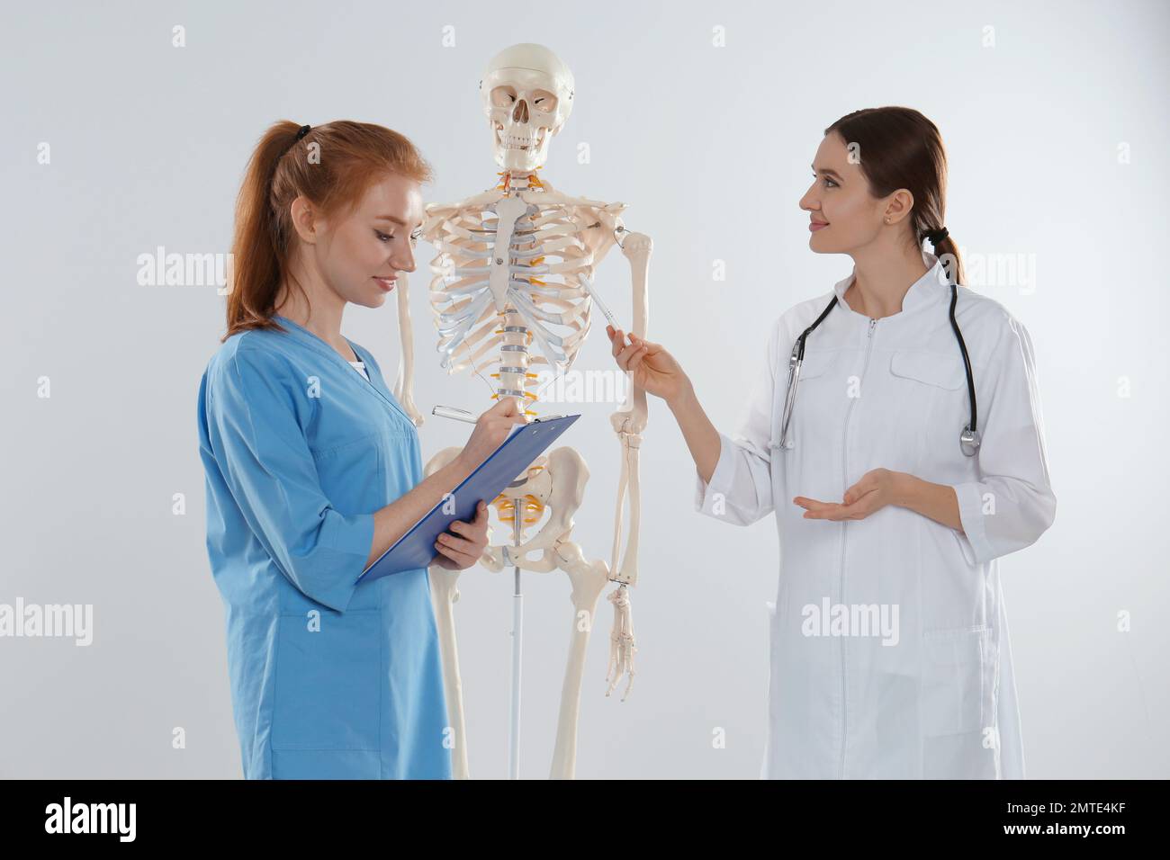 Professional orthopedist with human skeleton model teaching medical ...