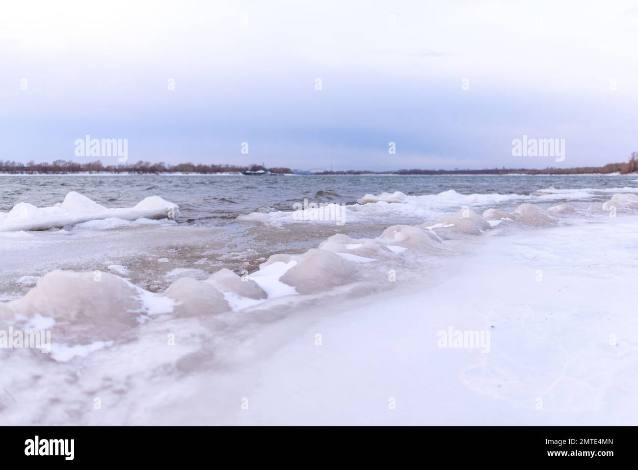 The first ice on the river bank rises in waves from the wind and ...