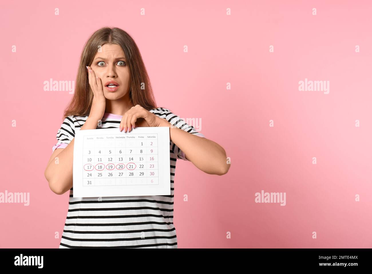Emotional young woman holding calendar with marked menstrual cycle days ...
