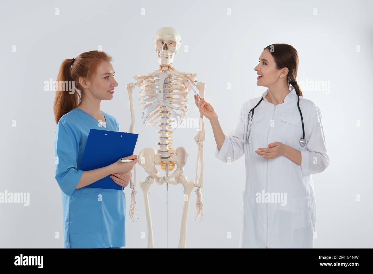 Professional orthopedist with human skeleton model teaching medical ...