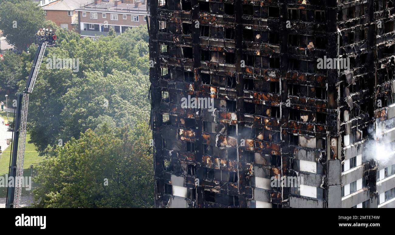 Firemen examine the scorched facade of the Grenfell Tower in London on ...