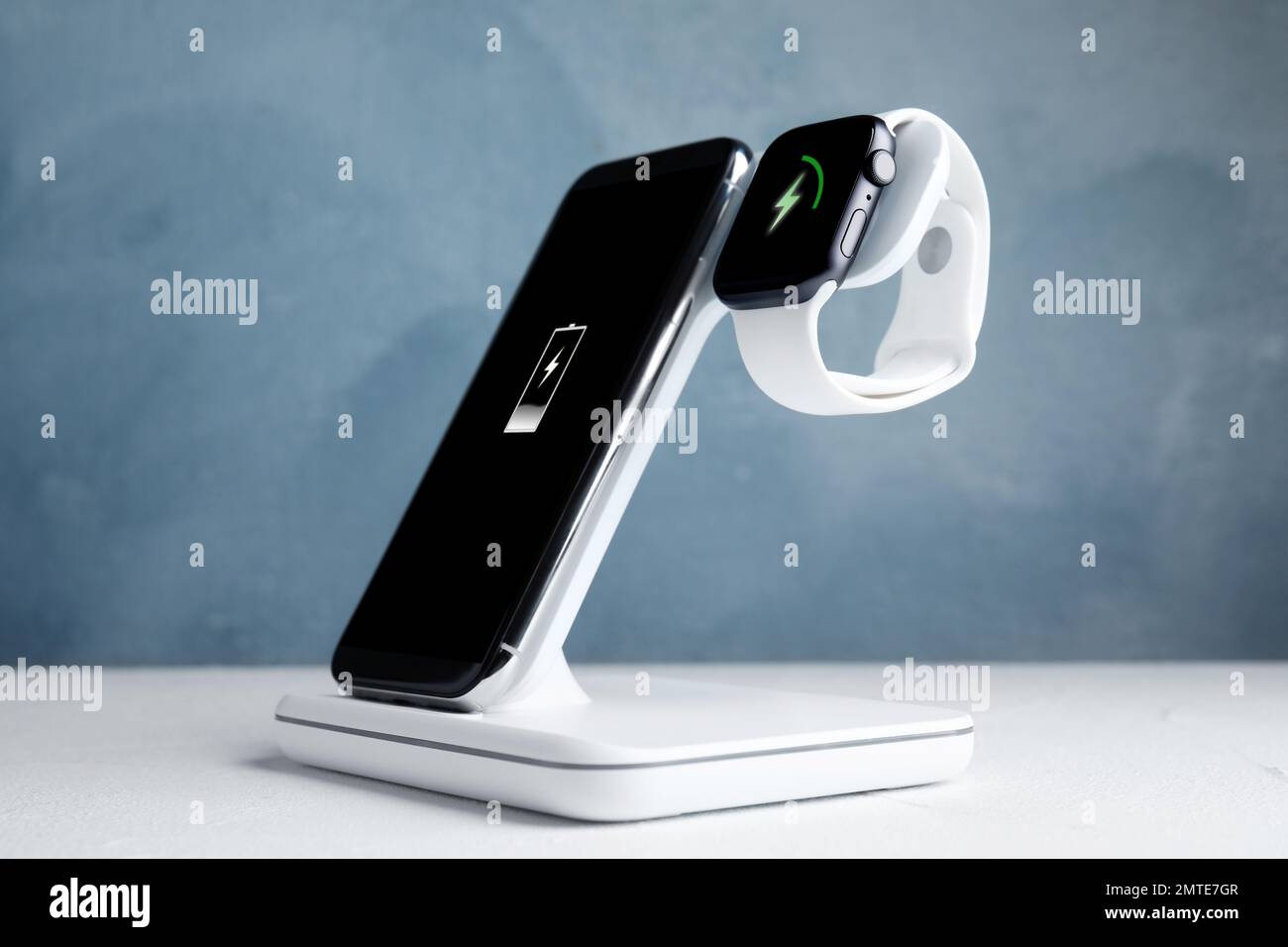 Mobile phone and smartwatch charging with wireless pad on white stone ...