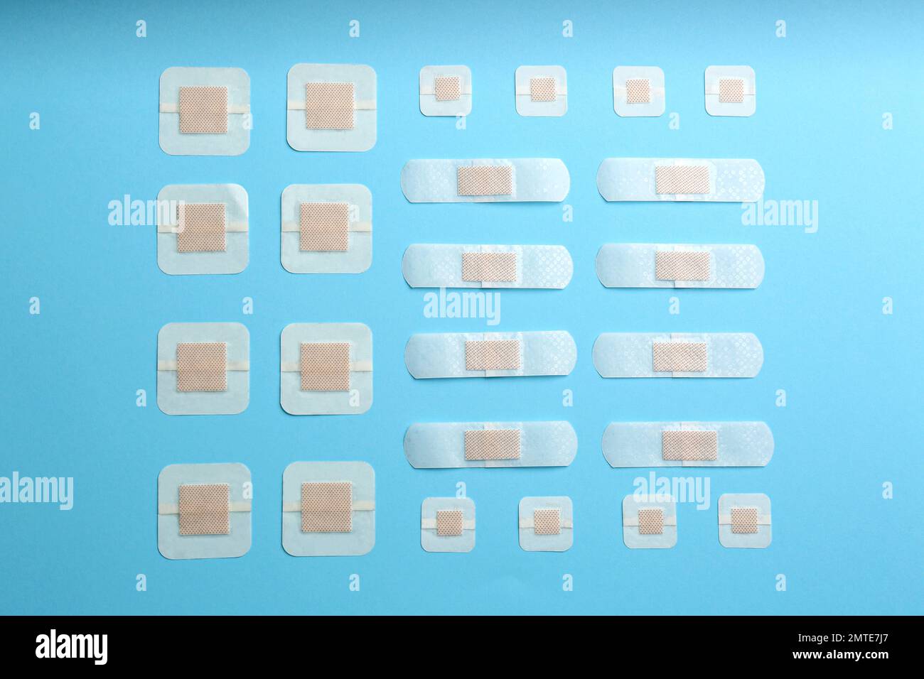Different types of sticking plasters on light blue background, flat lay ...