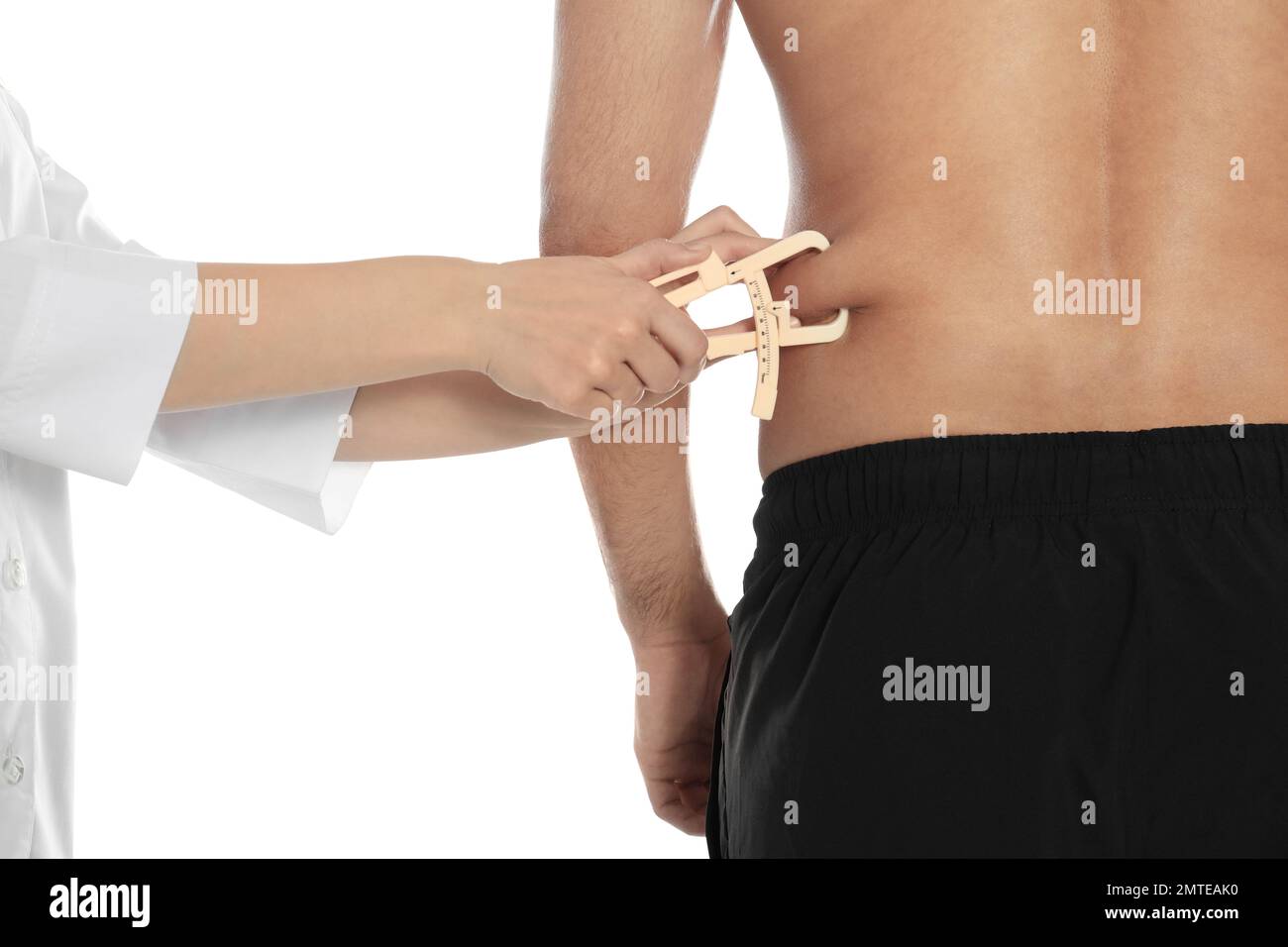 Nutritionist measuring man's body fat layer with caliper on white ...