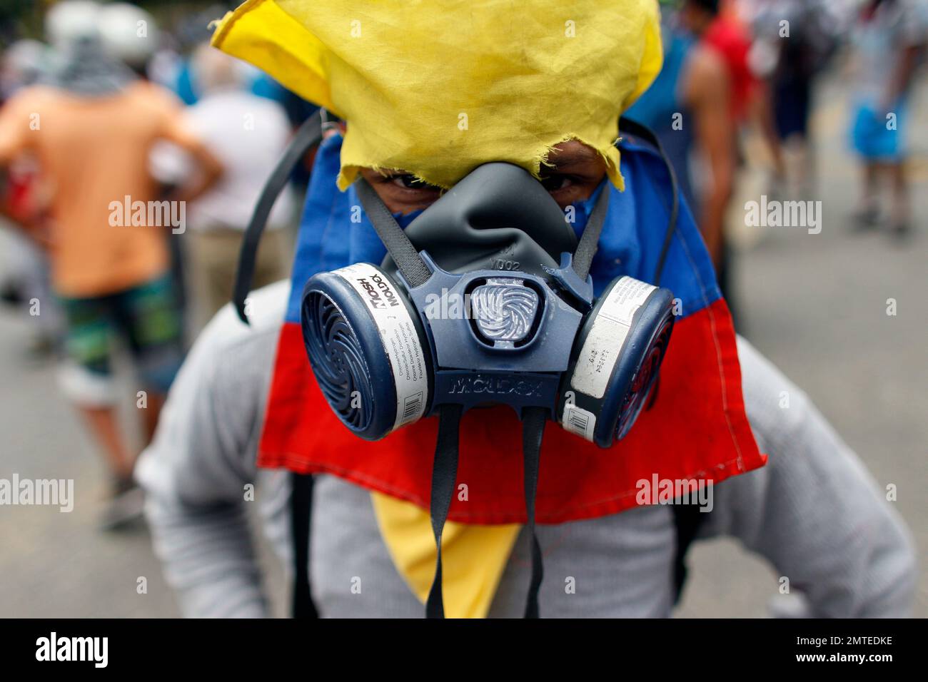 An anti-government demonstrator wears a gas mask and a Venezuelan flag ...