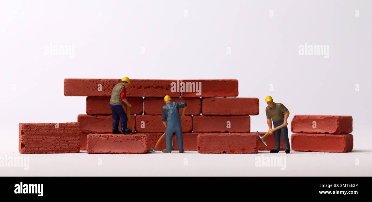 Miniature workers building bricks. Business concept with bricks and ...