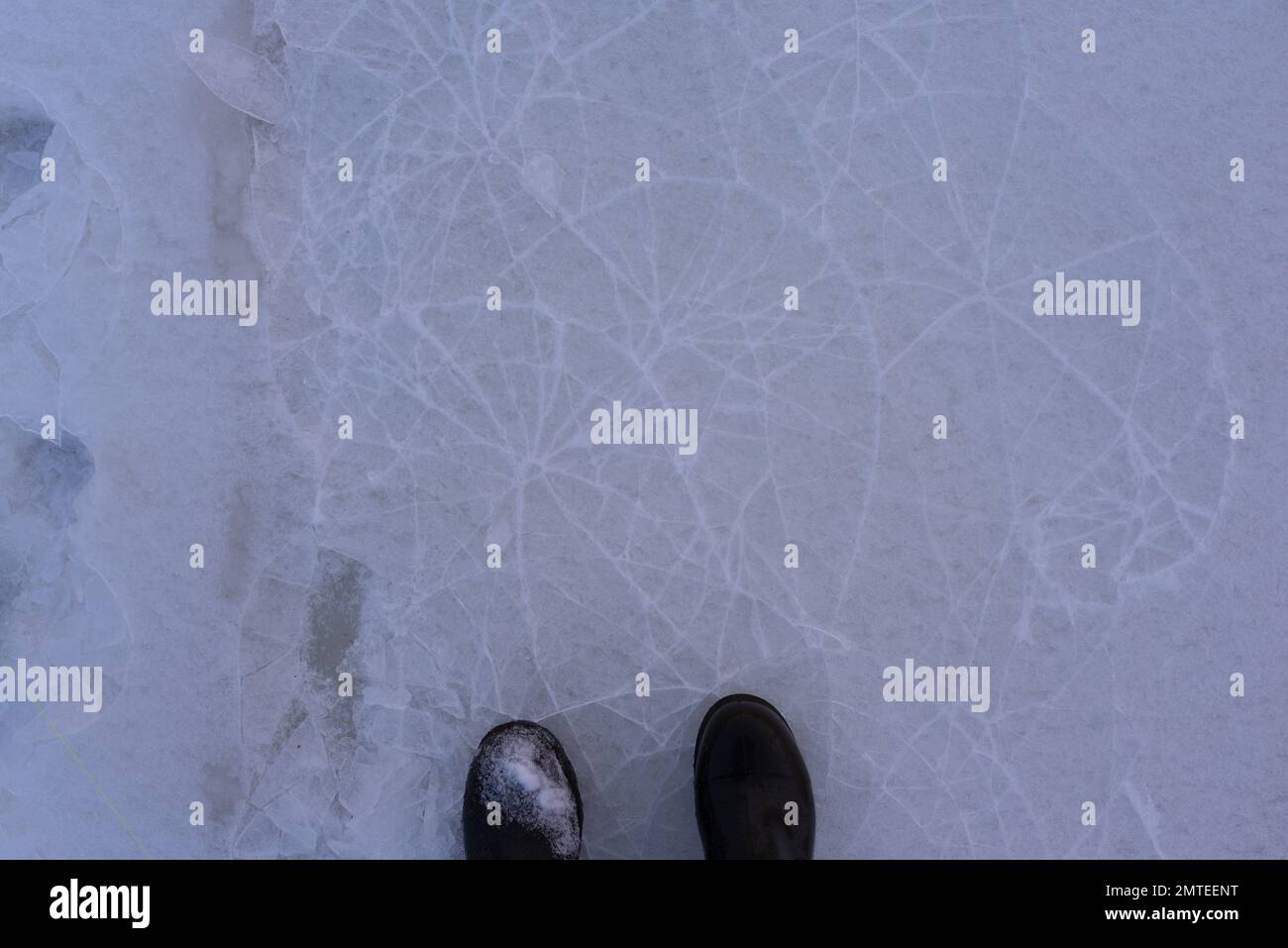 PARTS of the boots of the feet stand on the ice with cracks Stock Photo ...