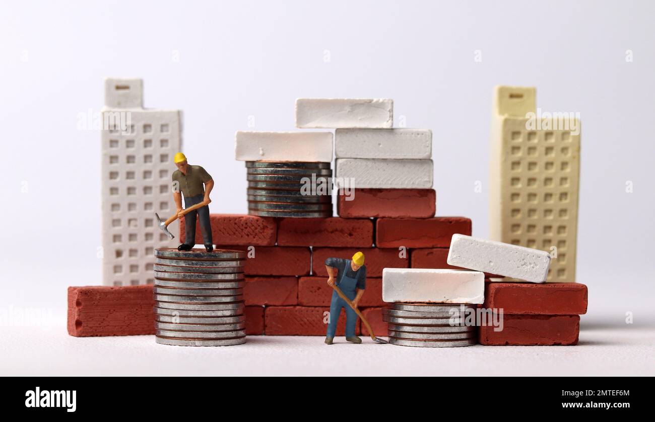 Miniature workers building bricks and miniature building. Business ...