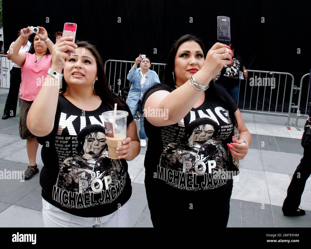 People gather and photograph a large screen showing images of Michael ...