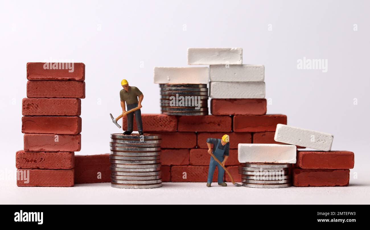 Miniature workers building bricks. Business concept with coins and ...