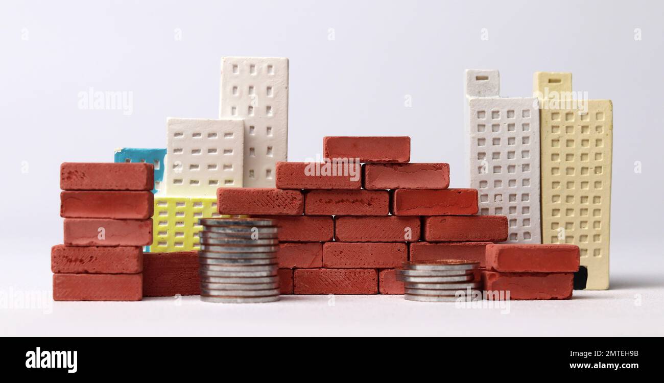 A pile of coins with miniature buildings and red brick. Business ...