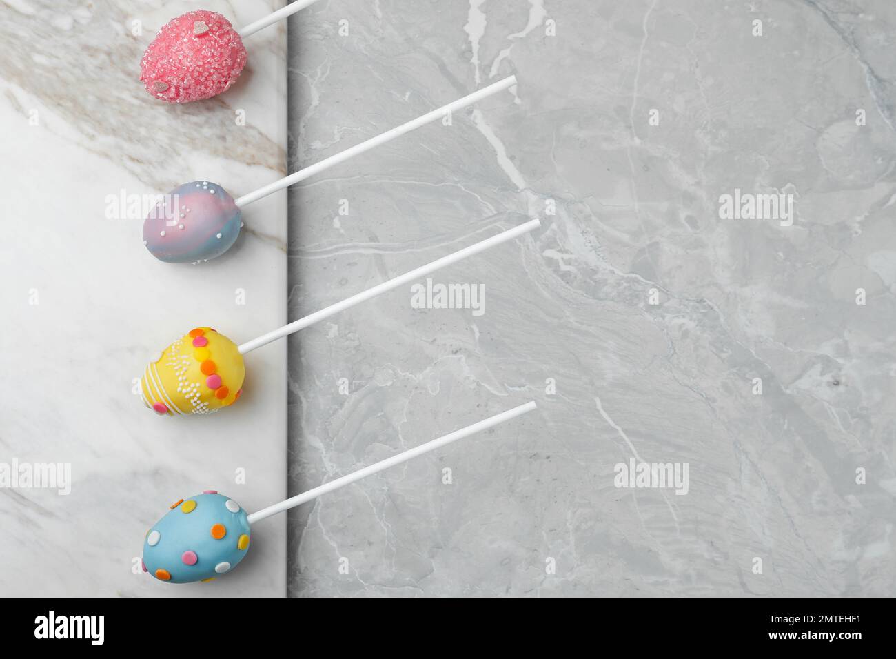 Egg shaped cake pops and space for text on grey marble table, flat lay ...