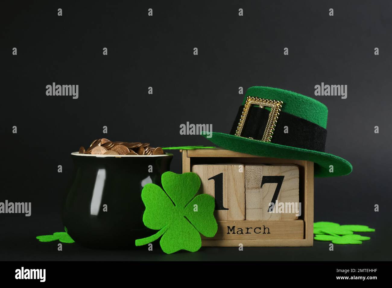 Composition with pot of gold coins and wooden block calendar on black ...