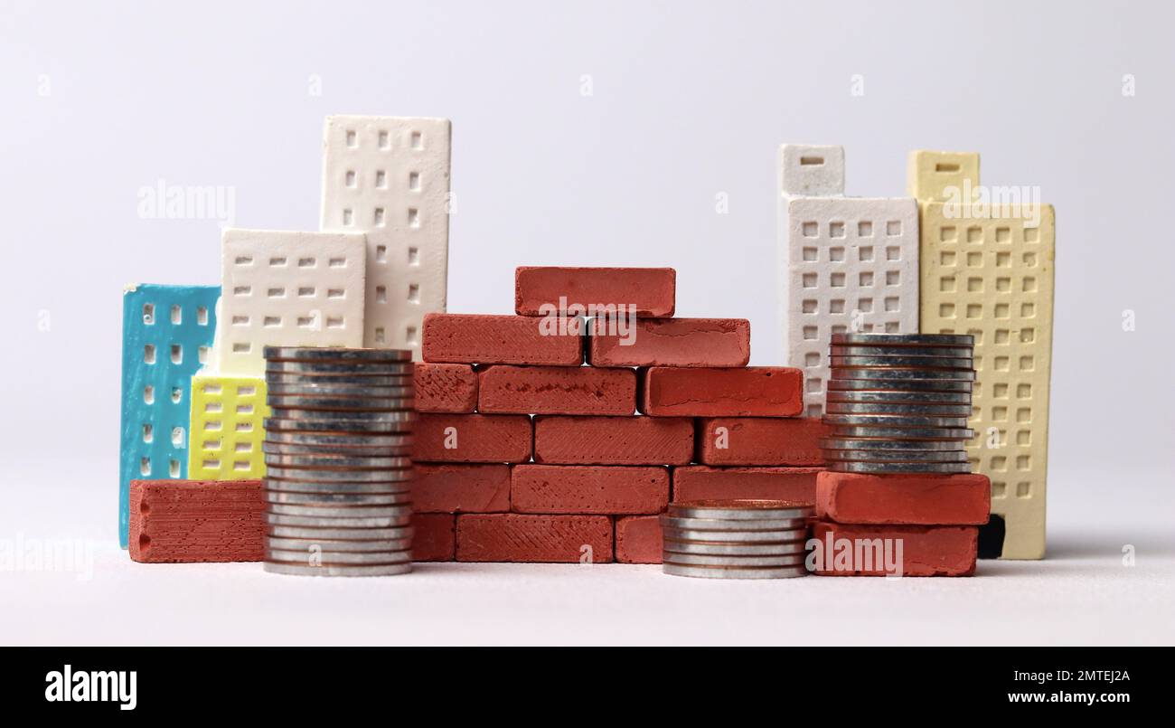 A pile of coins with miniature buildings and red brick. Business ...