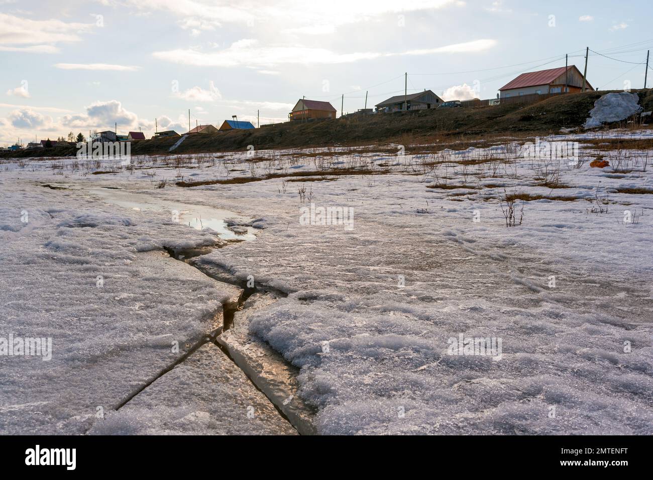 Spring cracked ice with snow on the shore near the ancient Suntar on ...