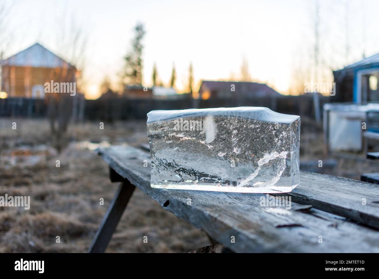 A transparent block of ice for use in drinking water stands on a rustic ...