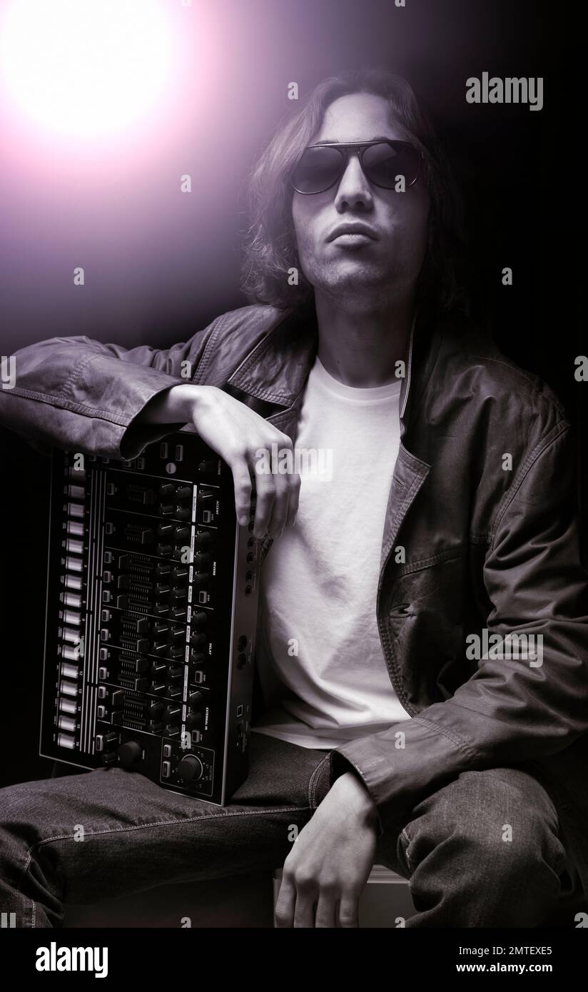 Young hip hop musician with a drum machine in stage with spot light ...