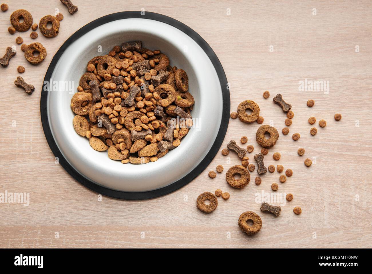 A bowl of dog food on a wooden floor. Dry feed pellets of various ...