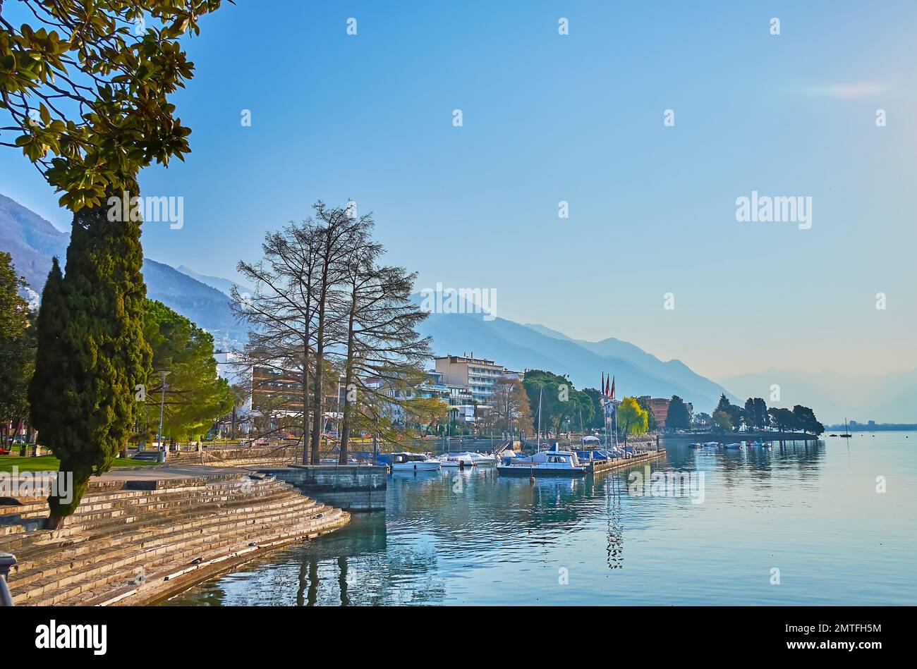 Beautiful park on the bank of Lake Maggiore with hazy mountains in ...