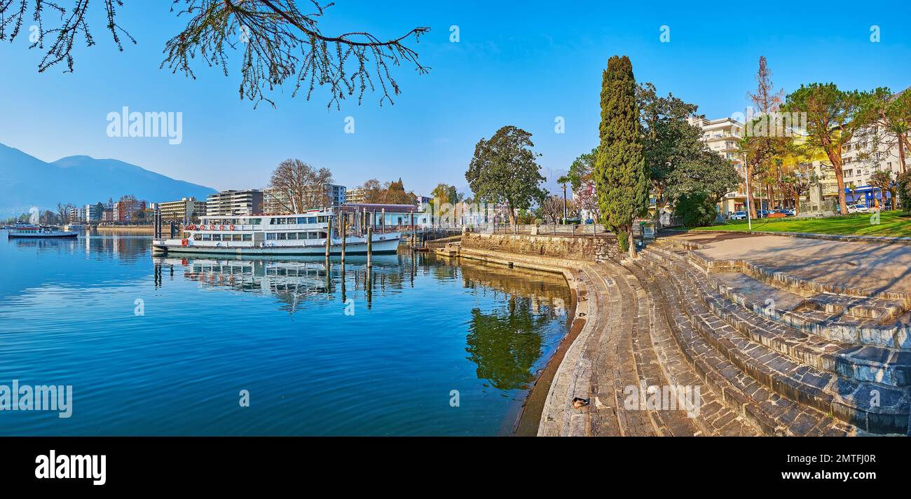 Panorama of embankment of Lake Maggiore with green park, moored ferry ...