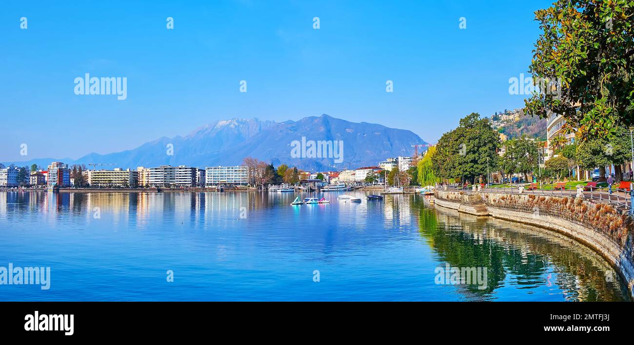 The hazy morning panorama of the calm blue waters of Lake Maggiore ...