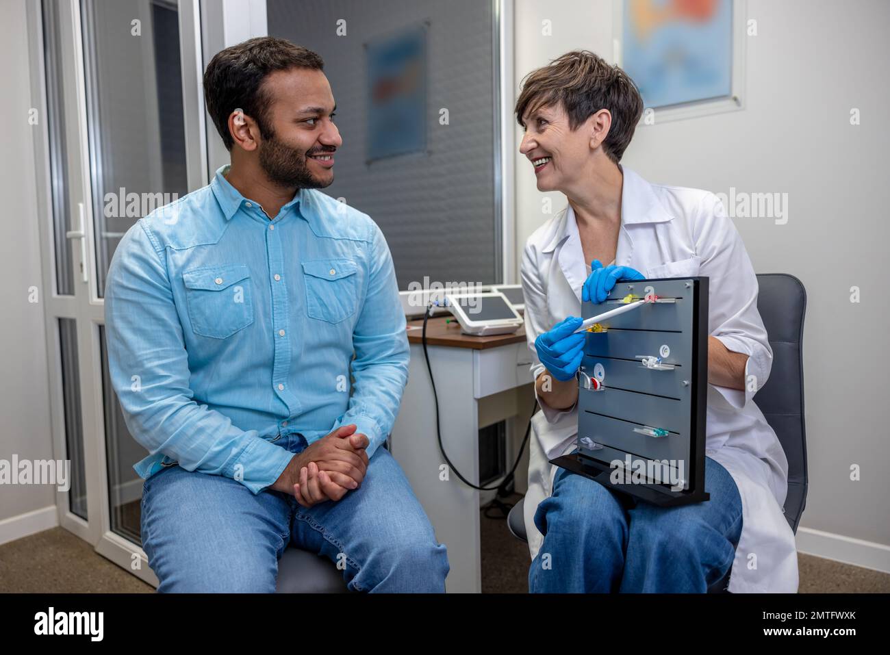 ENT doctor demonstrating hearing aid models to the patient Stock Photo ...