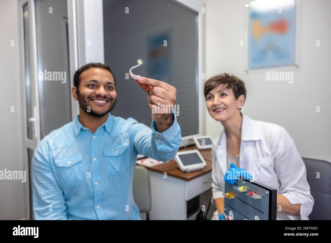 ENT doctor demonstrating hearing aid models to the patient Stock Photo ...