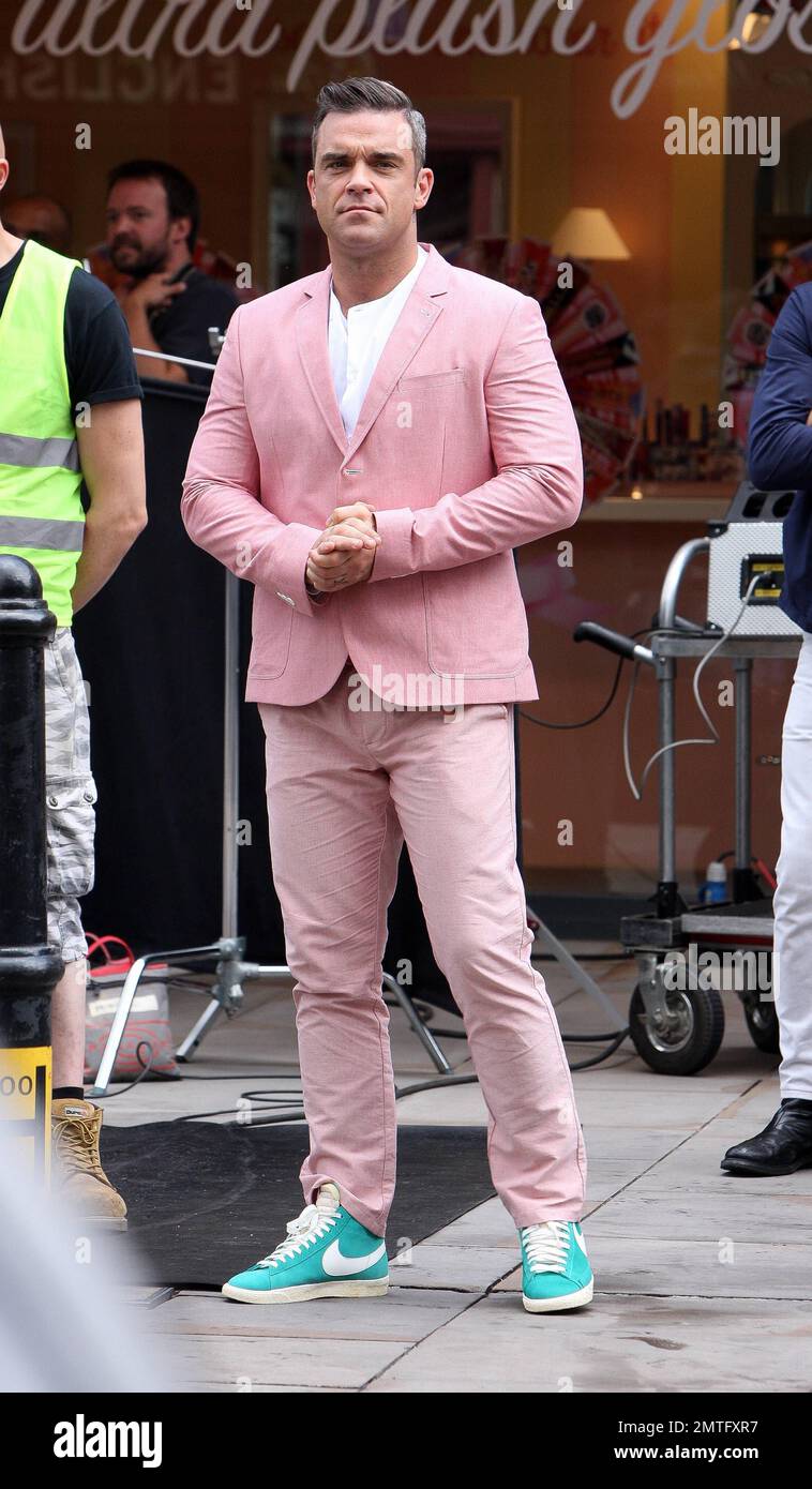 Wearing a pink suit with baby blue Nike sneakers, Robbie Williams and ...
