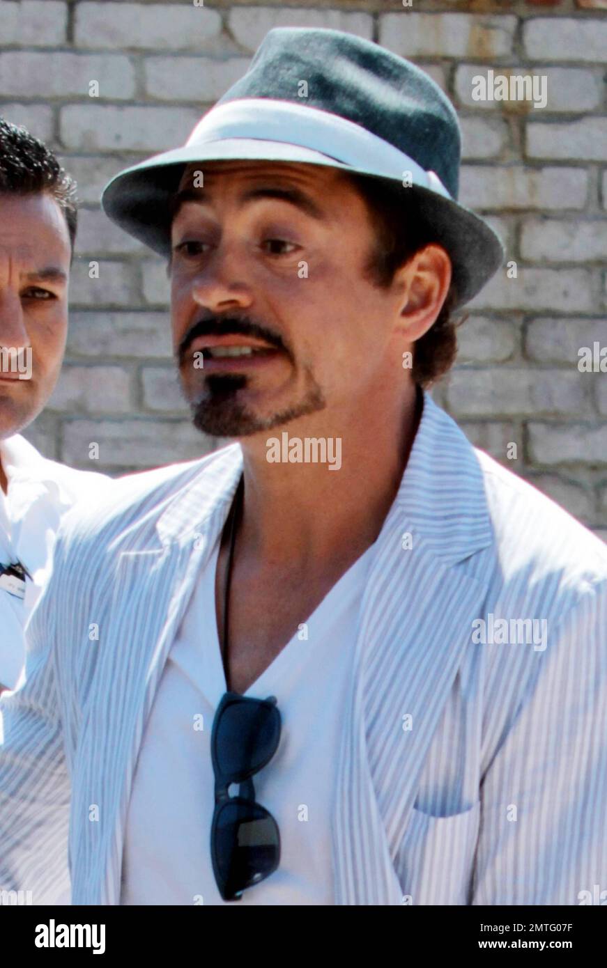 Wearing a black fedora and striped jacket with white pants and a t ...