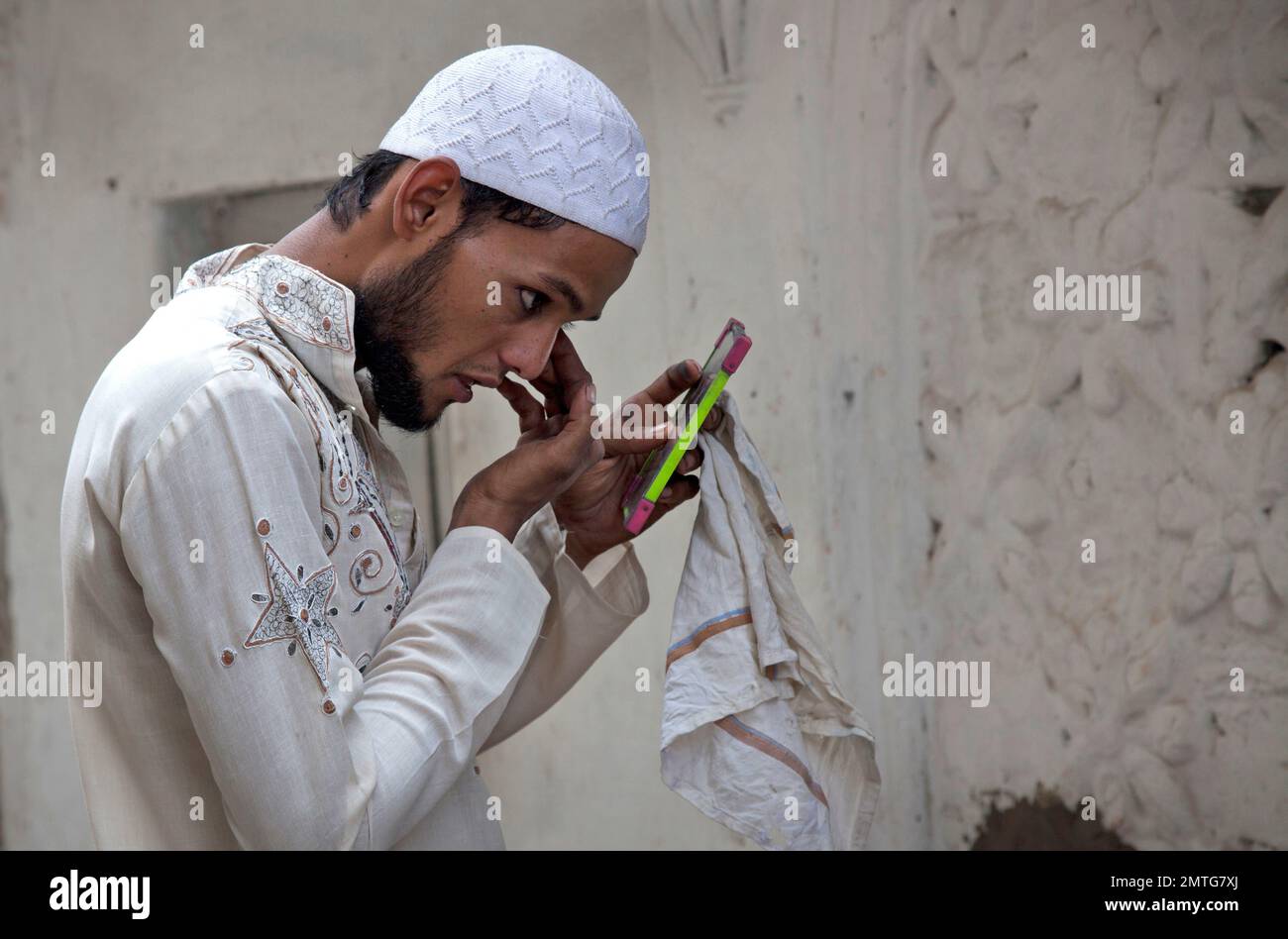 An Indian Muslim applies kohl before Friday prayers at a Mosque during ...