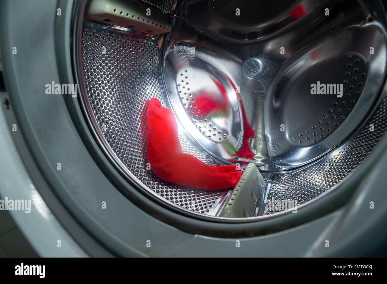Red sock in a washing machine drum - wide angle Stock Photo - Alamy