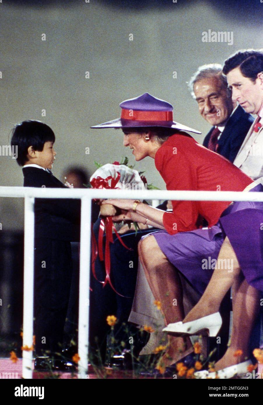 Princess Diana leans forward as she receives a bouquet of flowers from ...