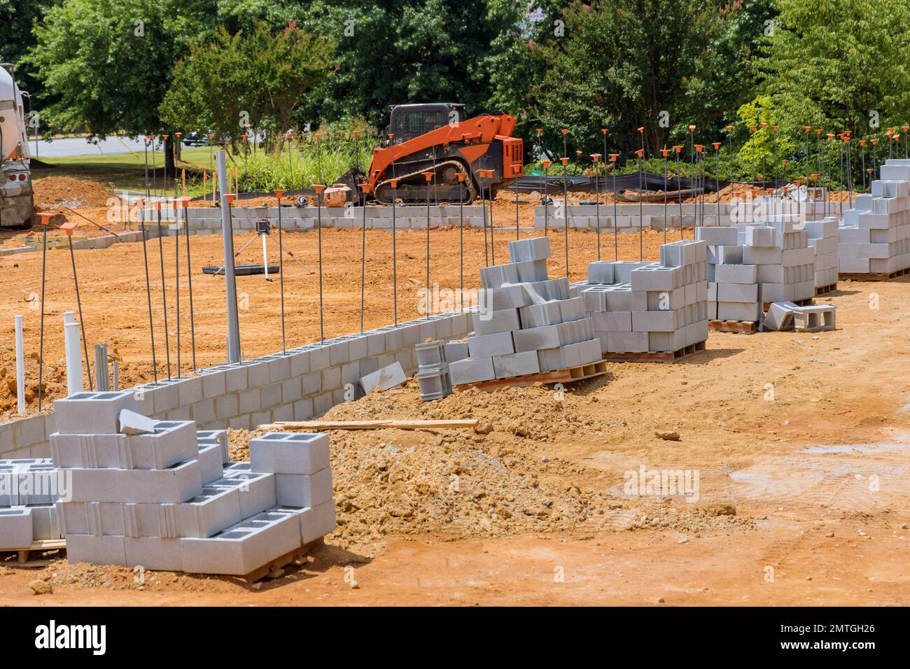 Construction site has pile cement blocks waiting to be laid on wall of ...